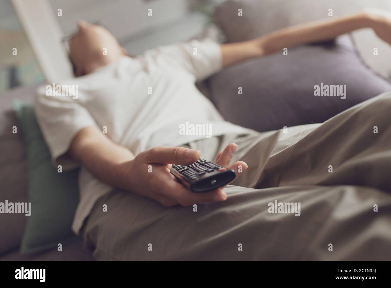 Bored woman falling asleep on the sofa while watching TV, she is ...