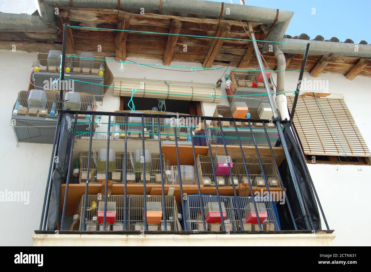 Low angle shot of a balcony in a building with lots of bird cages and ...