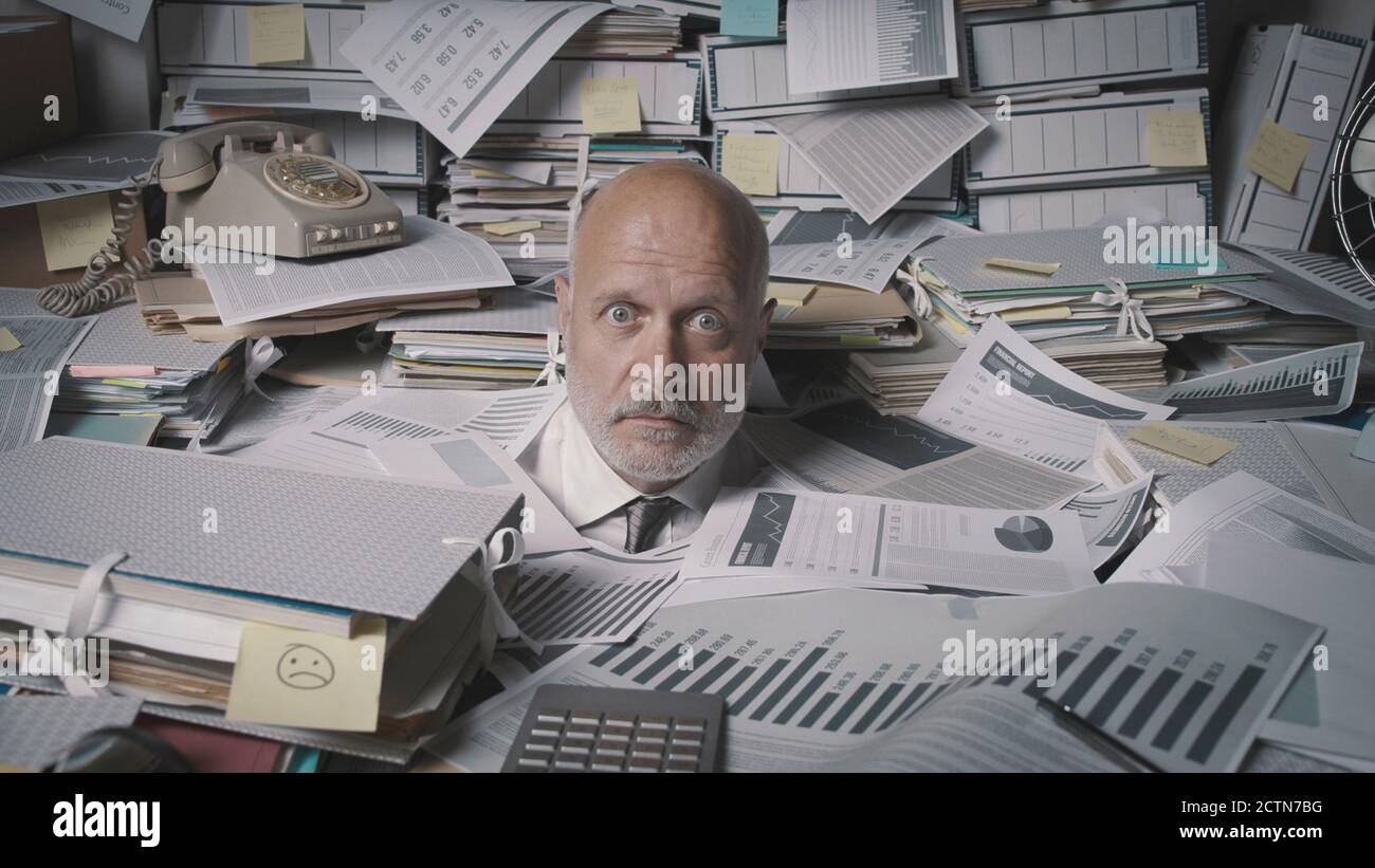 Stressed accountant working in the office, he is drowning under a lot ...