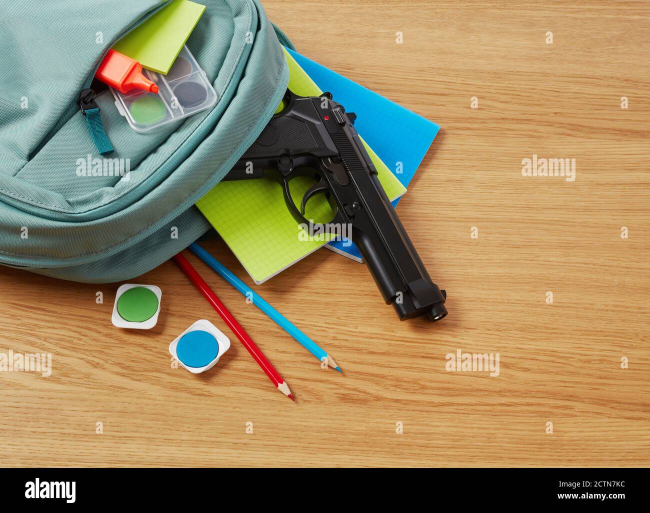 Backpack, school supplies and gun on desk Stock Photo - Alamy