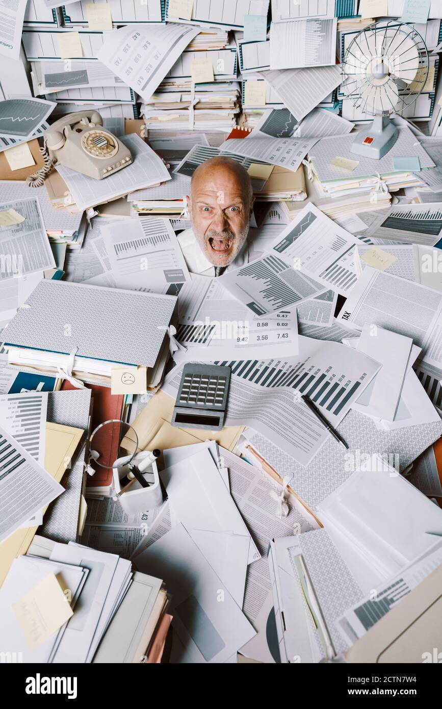 Screaming businessman drowning under a lot of paperwork in the office ...