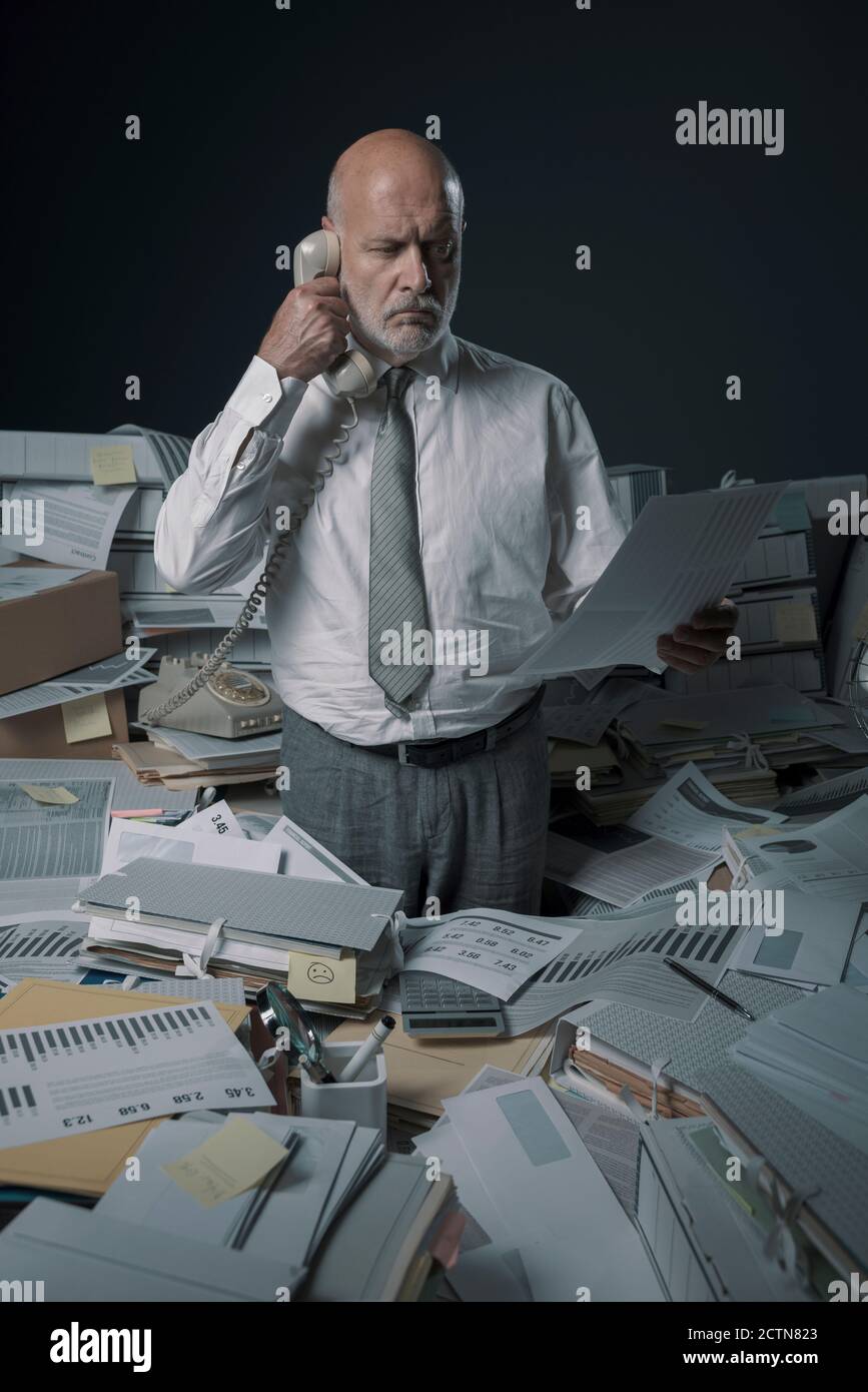 Confused stressed office worker answering phone calls, he is surrounded ...