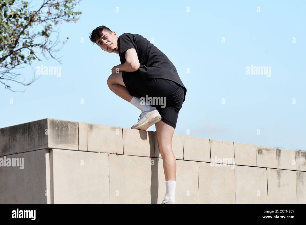 Side view of young male jumping on concrete wall of building while ...