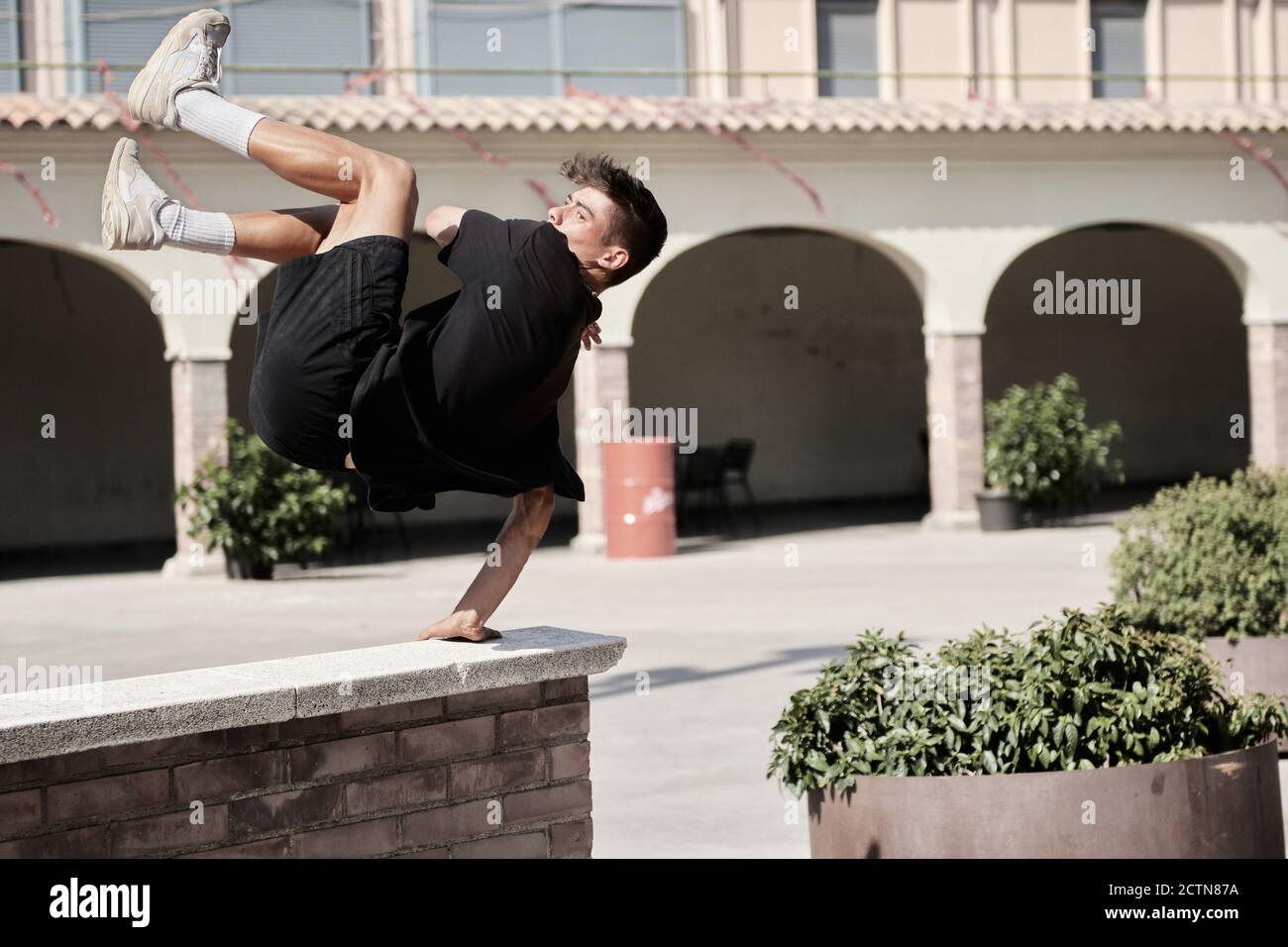 Side view of concentrated male jumping over stone fence and balancing ...