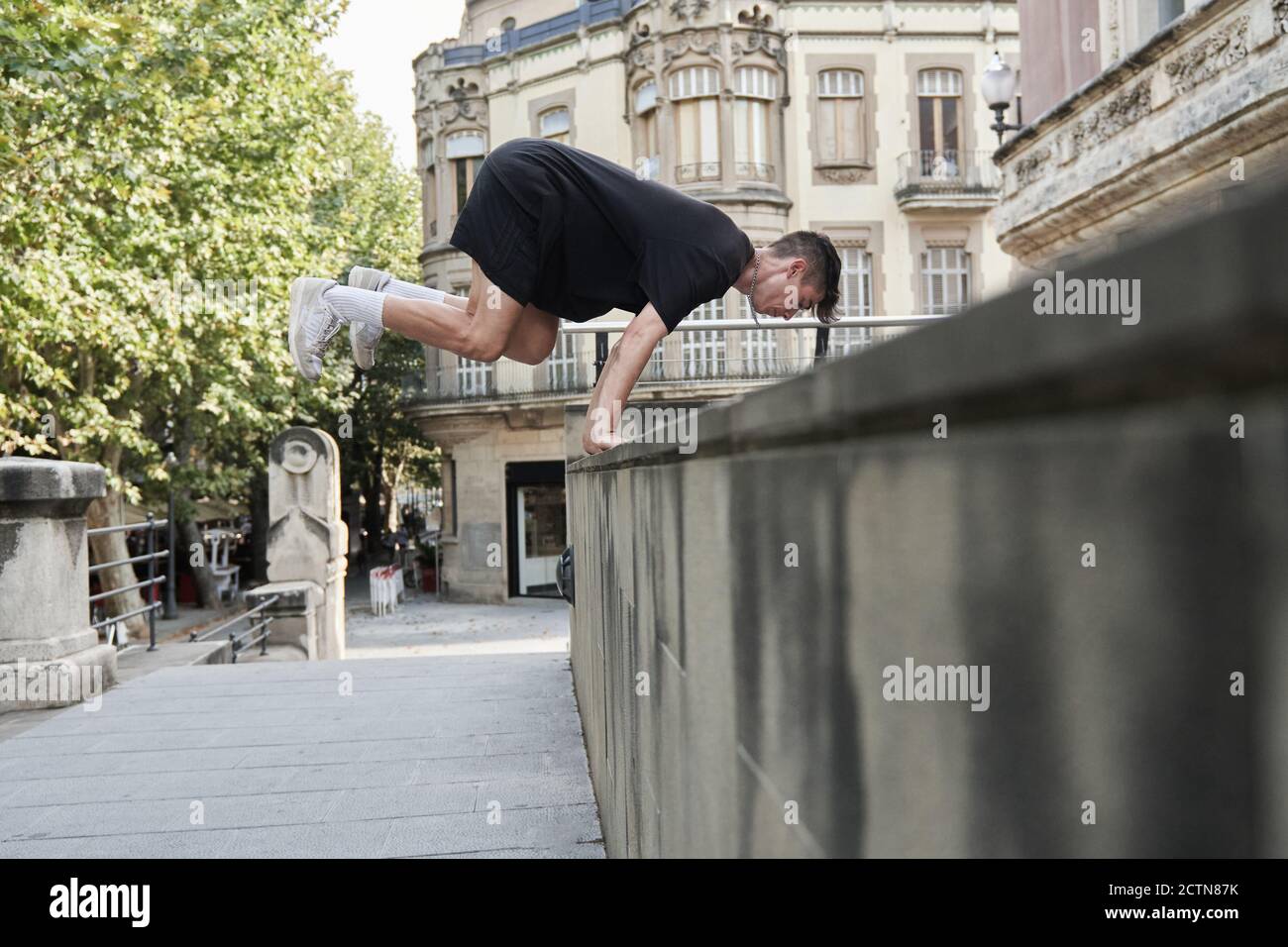 Side view of concentrated male jumping over stone fence and balancing ...