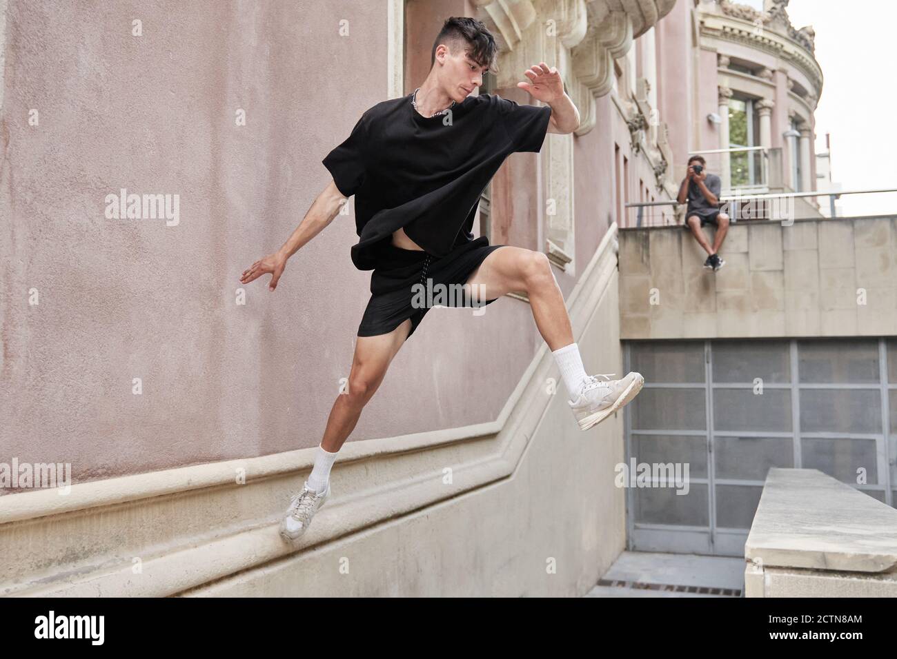 Side view of concentrated male jumping over stone fence and balancing ...