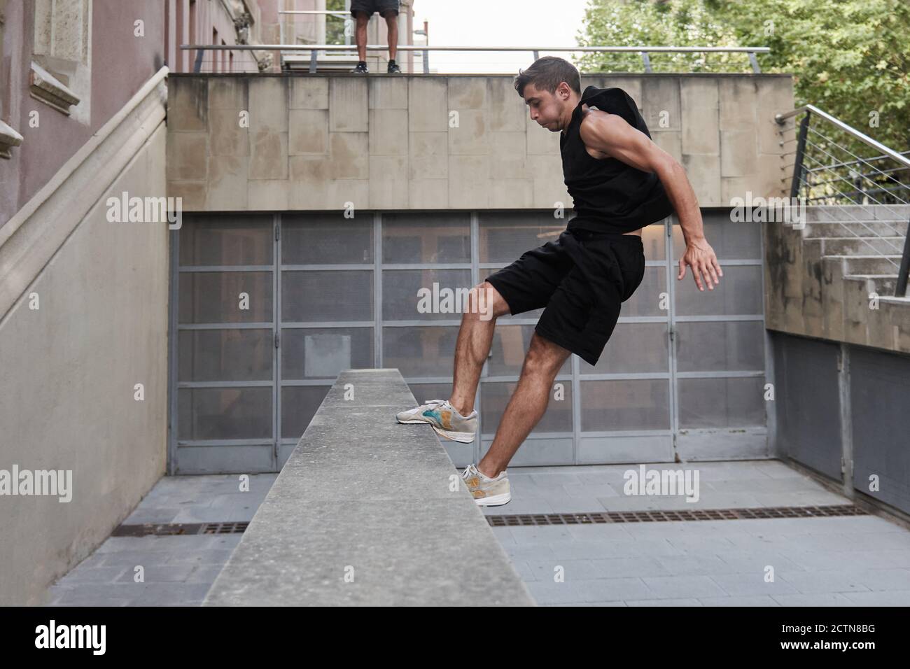 Side view of concentrated male jumping over stone fence while ...