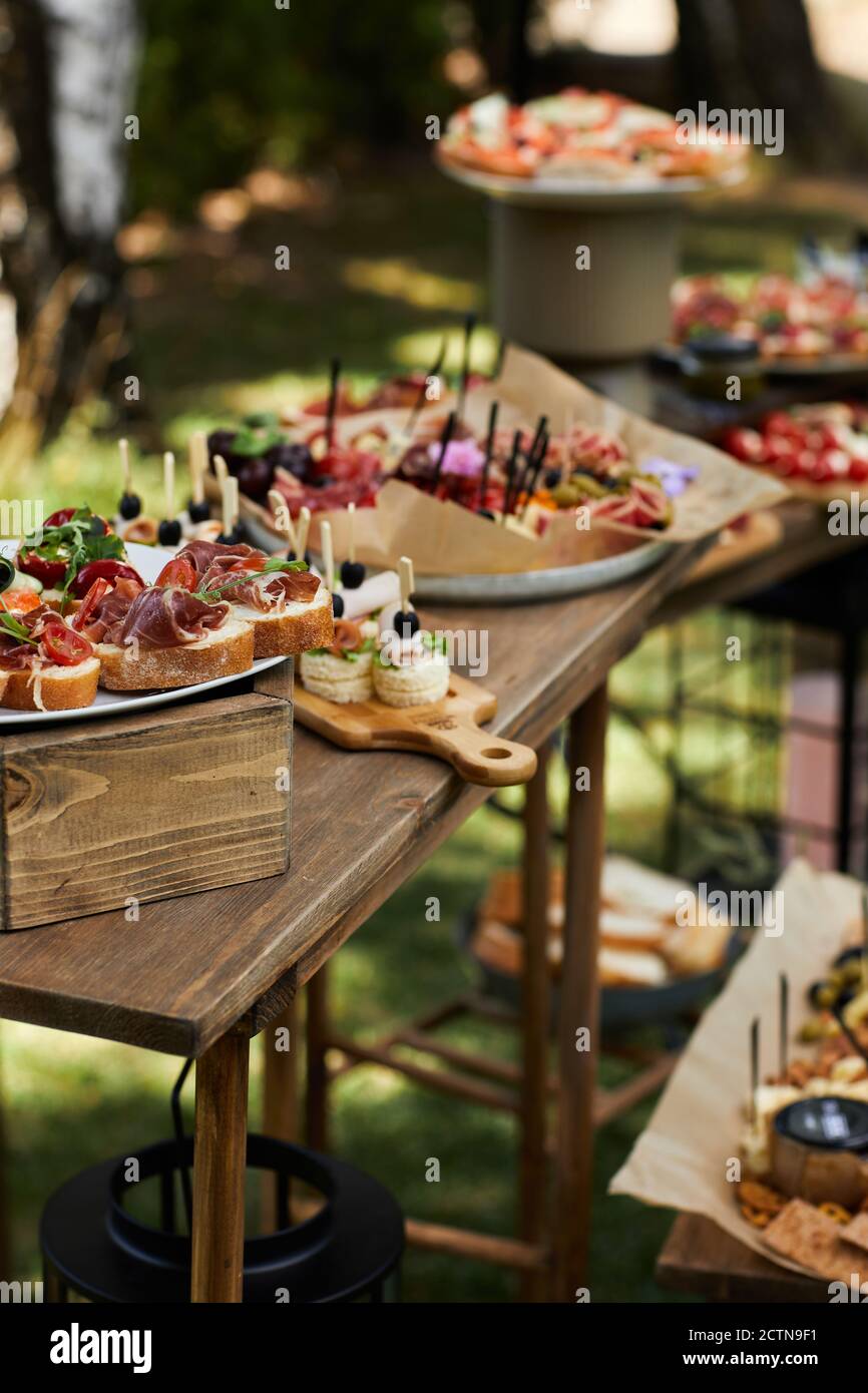 wooden buffet table with snack, appetizer and fruits decorated outdoor ...