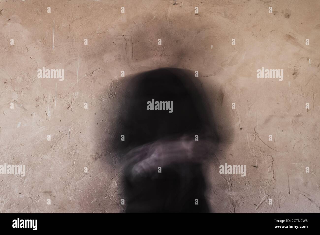 A blurred, ghostly figure with no head. Standing in fromt of a textured ...
