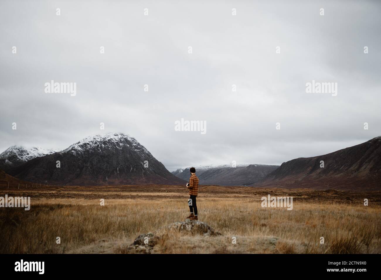 Back view of unrecognizable male explorer standing on rock and enjoying ...