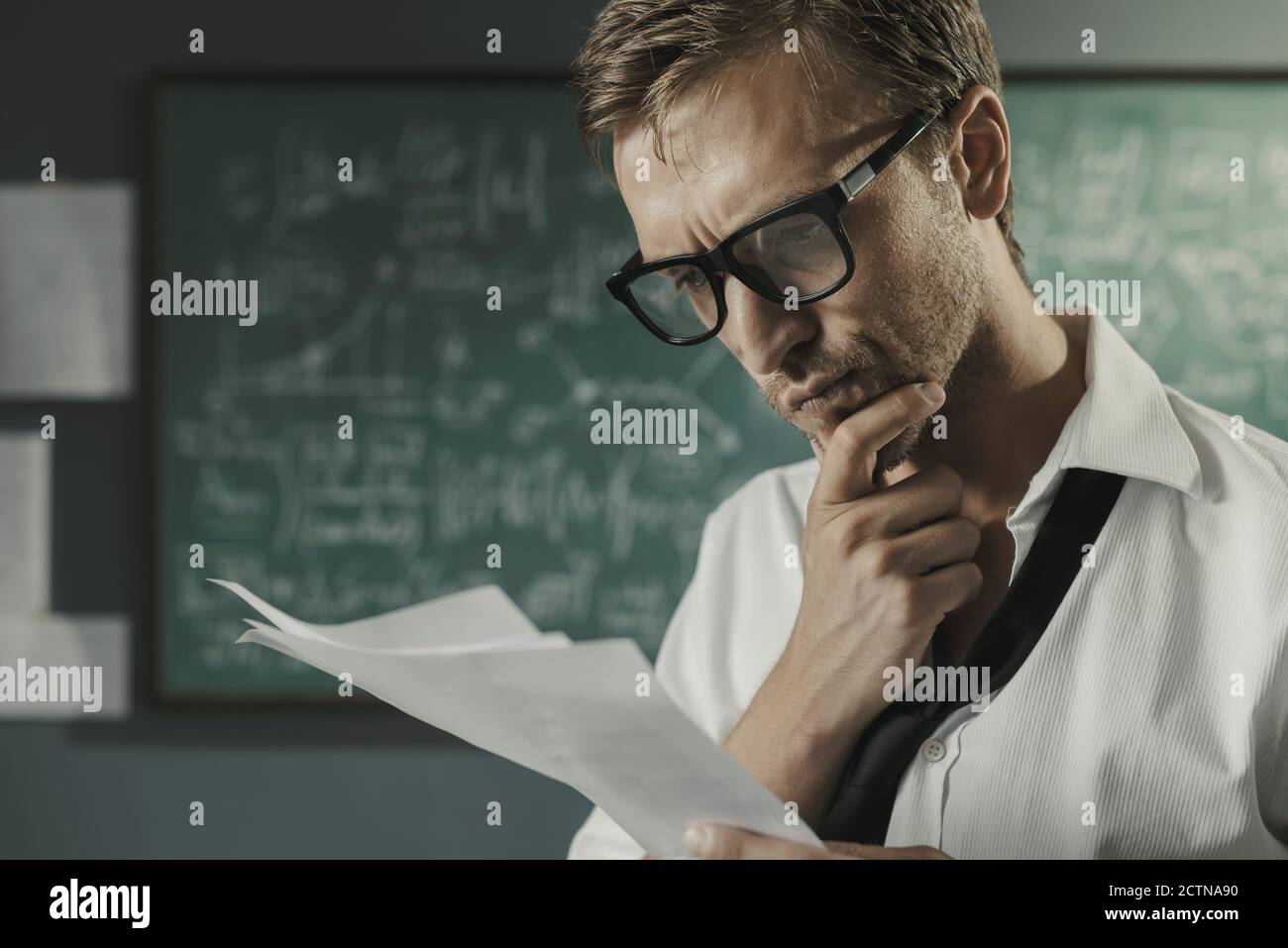 Young mathematician studying in his office and reading papers, he is ...