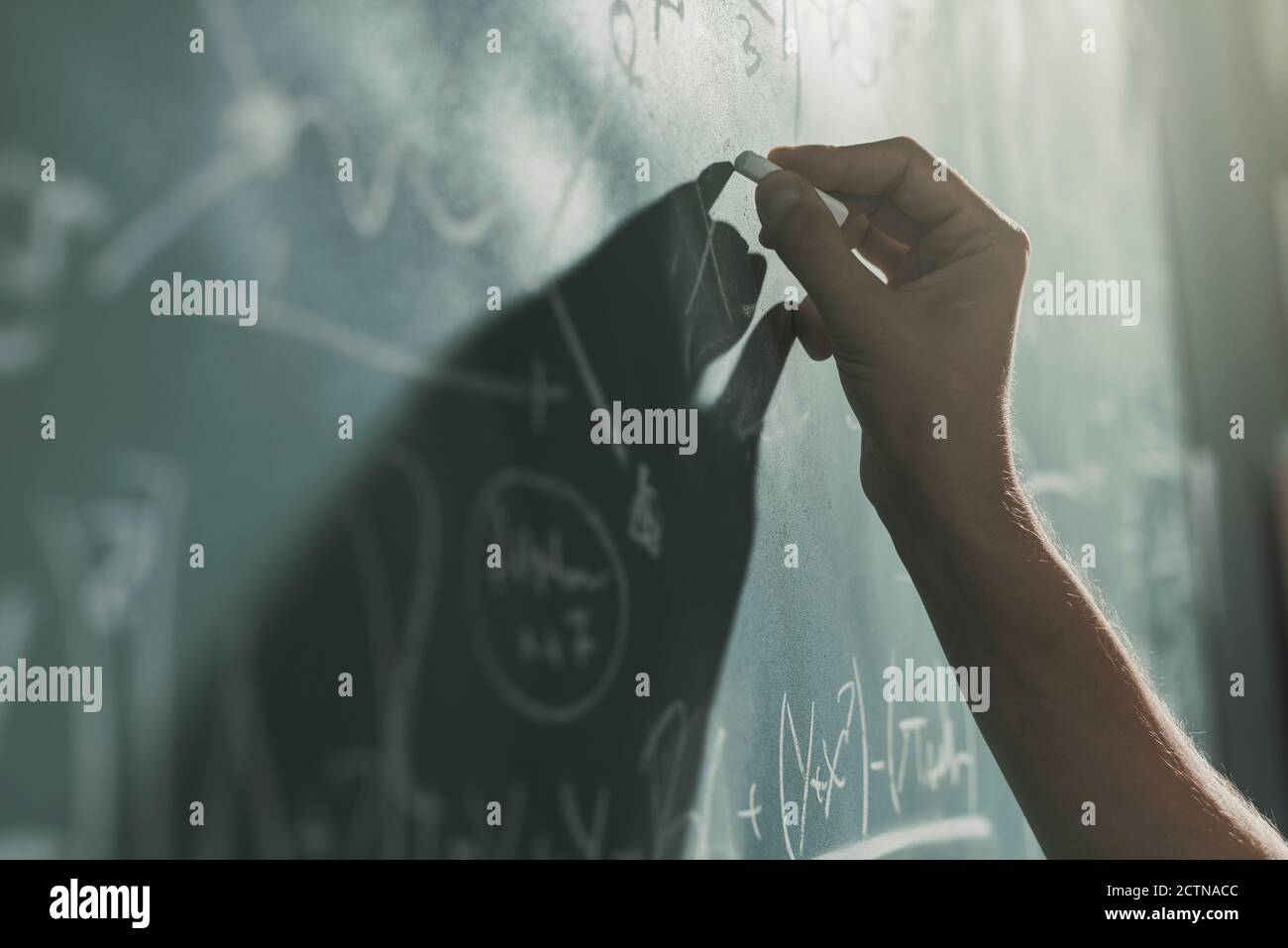 Professor writing mathematical formulas on the chalkboard, hand close ...