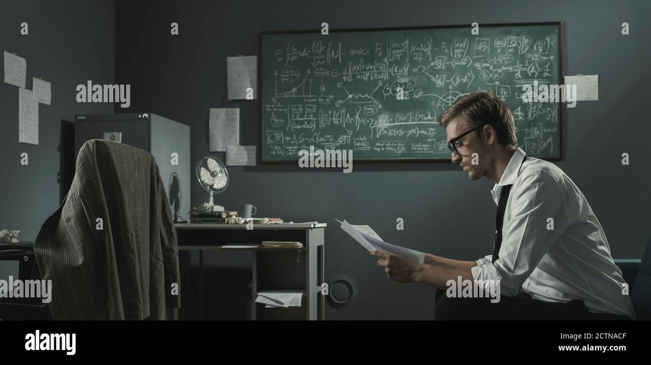 Brilliant mathematician working in his office, he is reviewing his ...