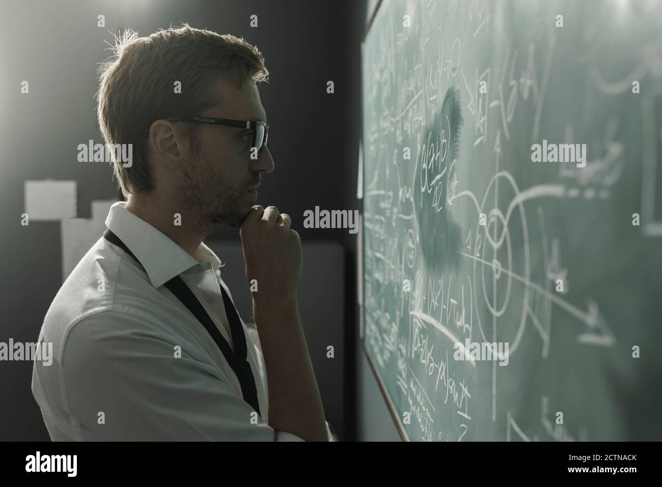 Young smart mathematician drawing math formulas on the chalkboard and ...