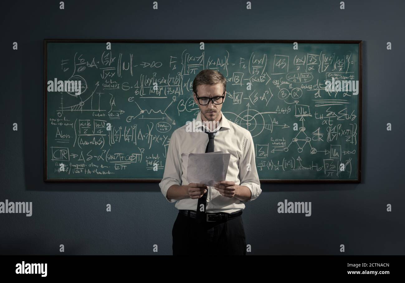Confident young math professor standing in front of the chalkboard and ...