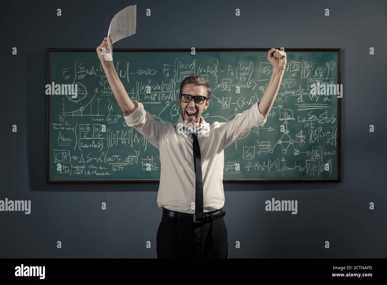 Cheerful successful mathematician standing in front of a chalkboard ...