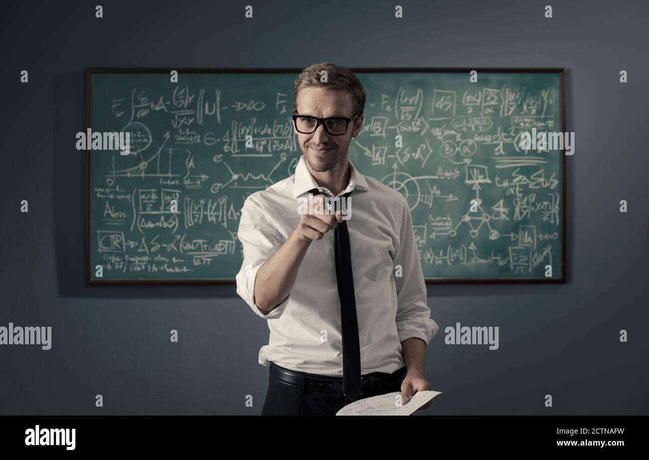 Confident smiling professor standing in front of a chalkboard with math ...