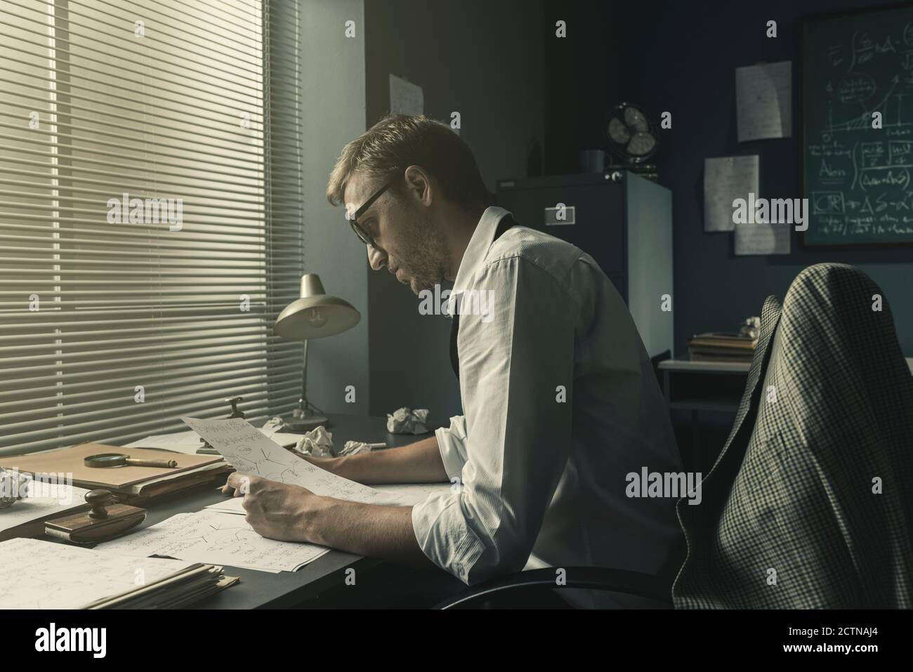 Young creative mathematician sitting at desk and working in the office ...