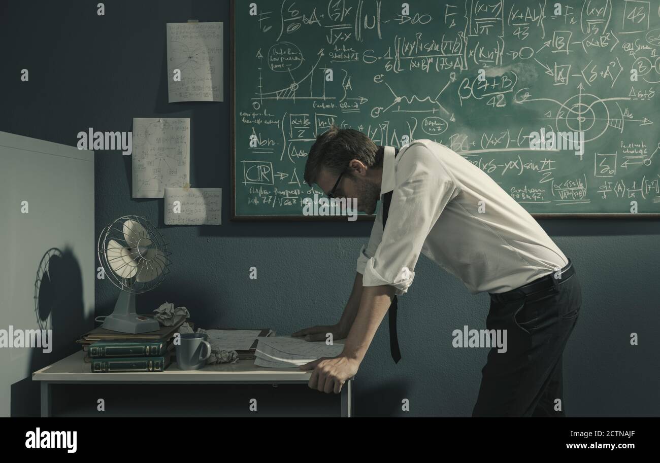 Brilliant mathematician working in his office, he is reviewing his ...