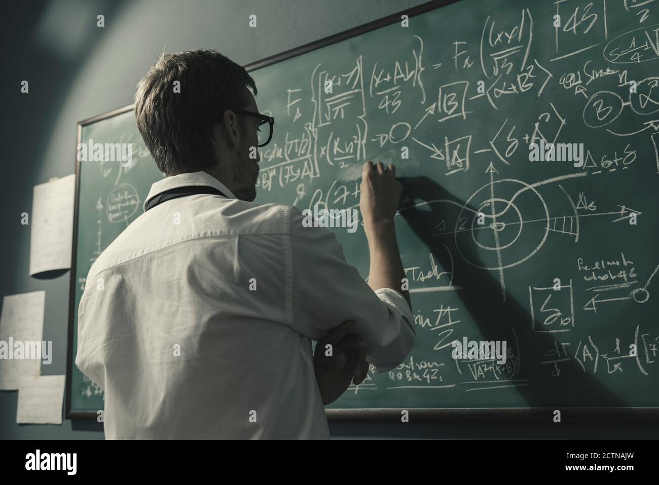 Young smart mathematician drawing math formulas on the chalkboard and ...
