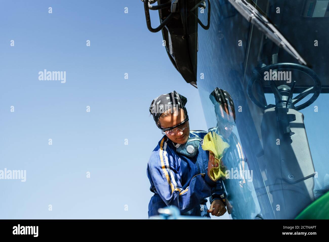 Side view low angle of busy female worker in uniform washing window of ...