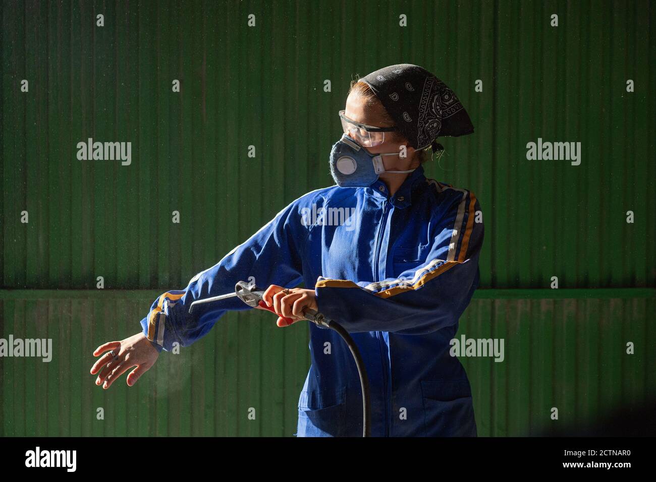 Concentrated female mechanic in uniform and mask checking air ...