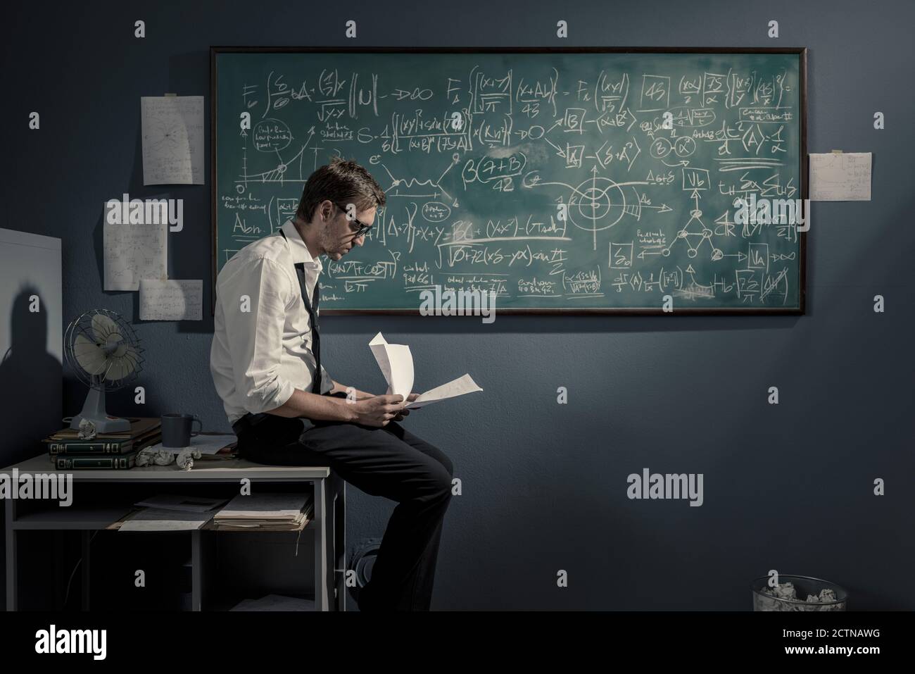 Brilliant mathematician working in his office, he is reviewing his ...