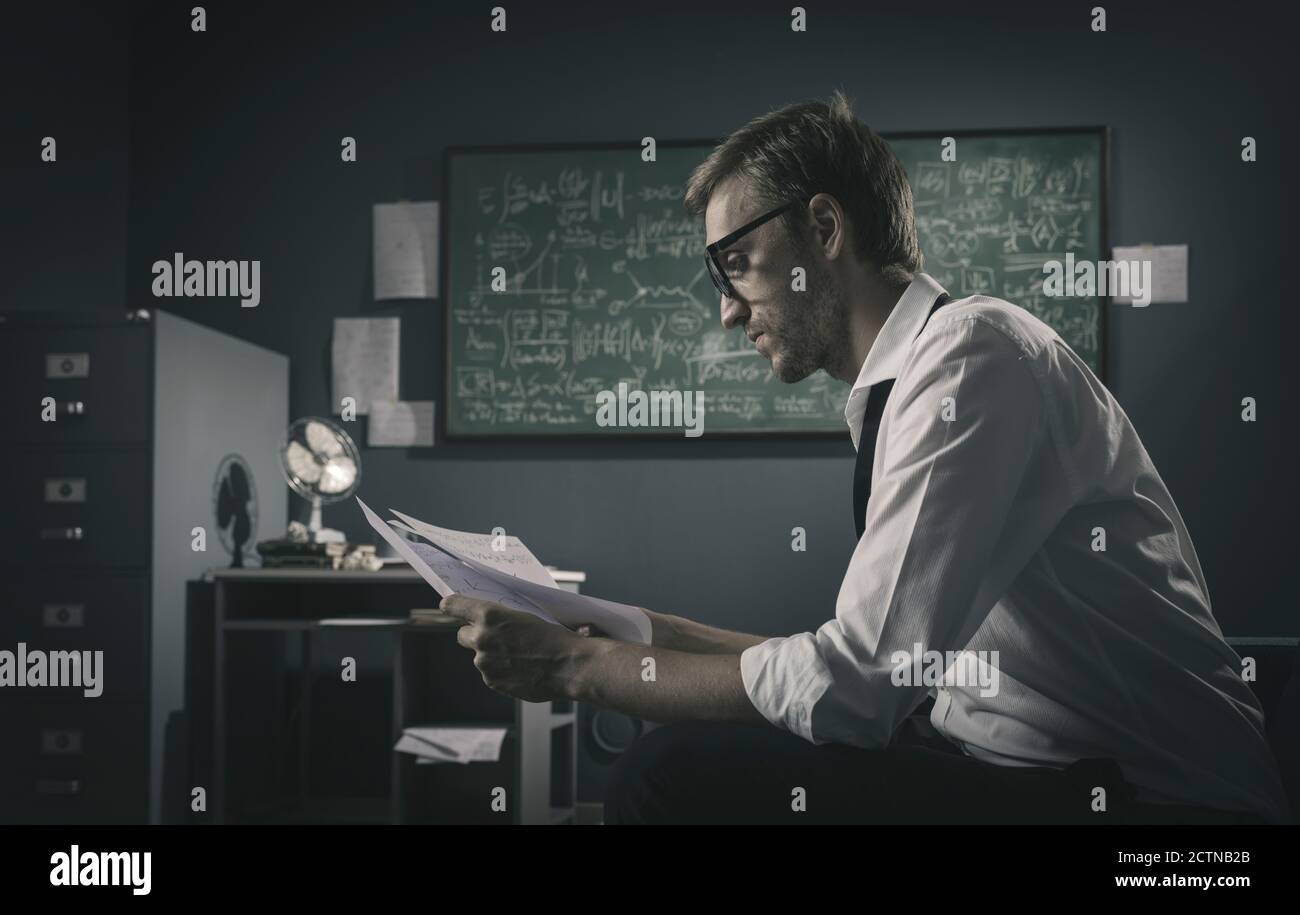 Brilliant mathematician working in his office, he is reviewing his ...
