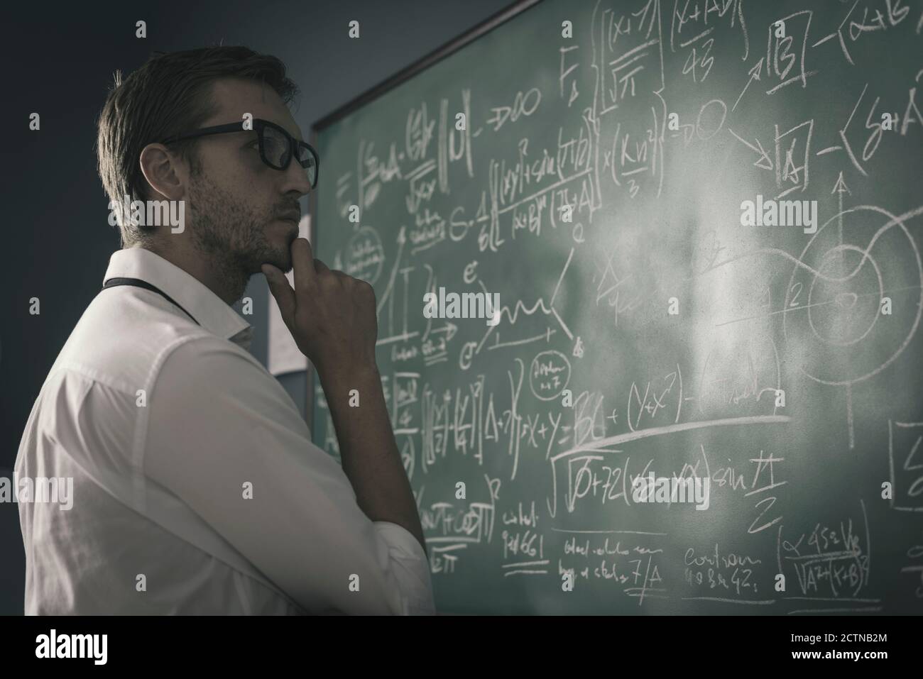 Mathematician reviewing math formulas on the chalkboard, he is thinking ...