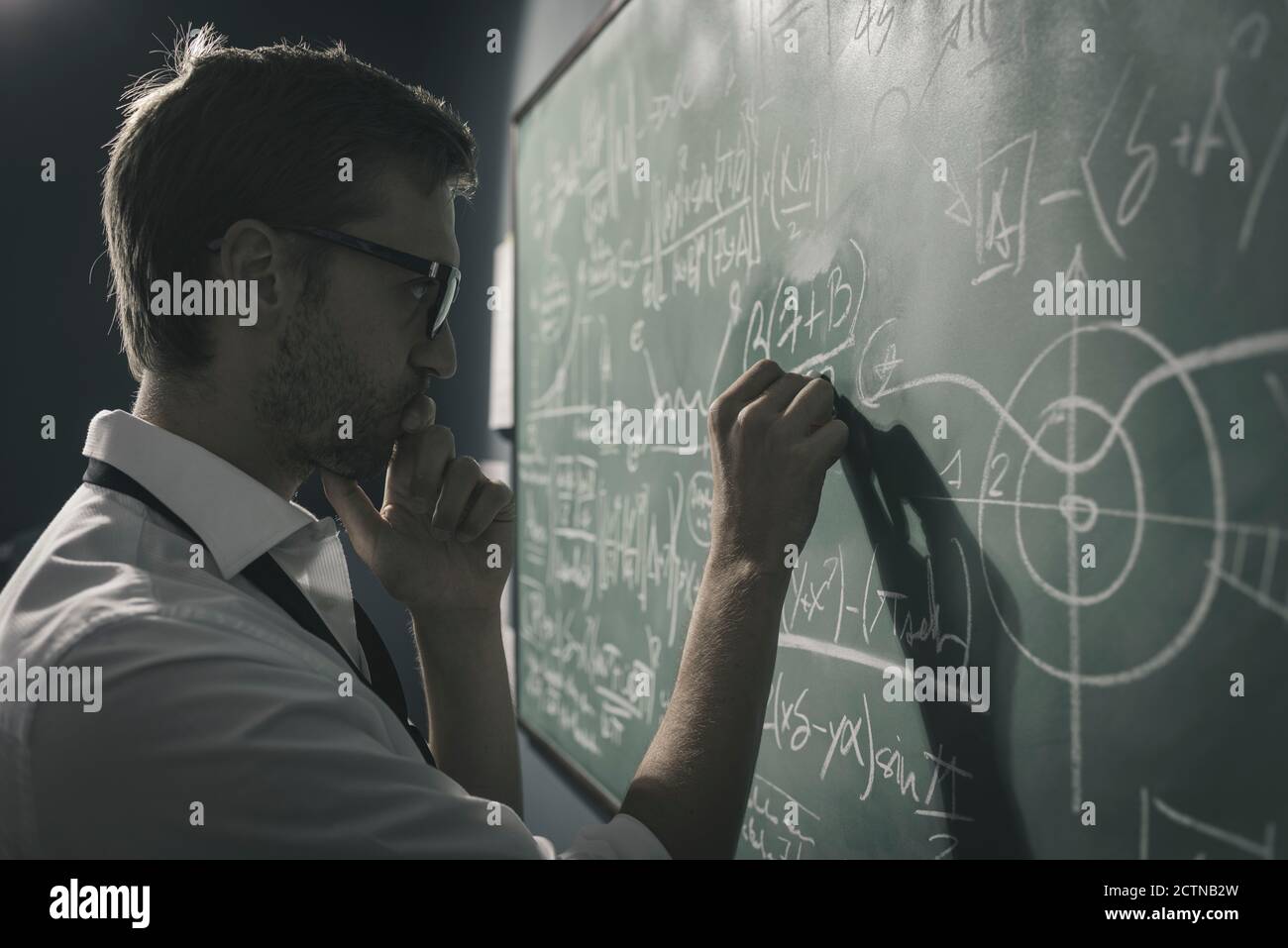Young smart mathematician drawing math formulas on the chalkboard and ...