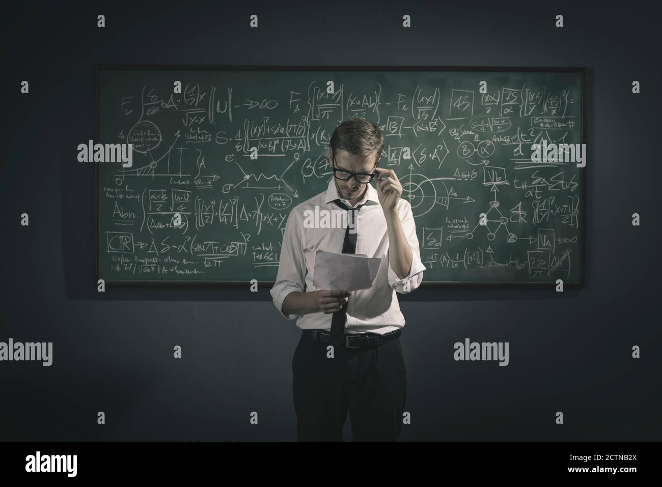 Confident young math professor standing in front of the chalkboard and ...