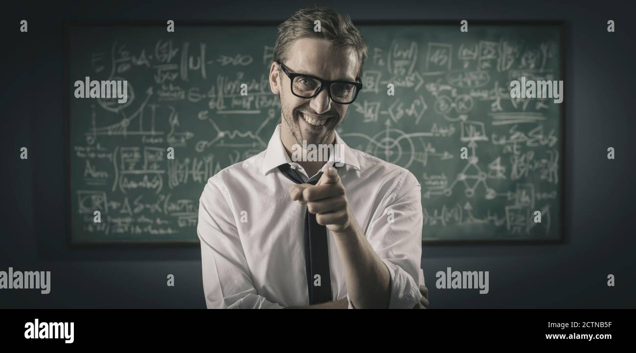 Confident smiling professor standing in front of a chalkboard with math ...