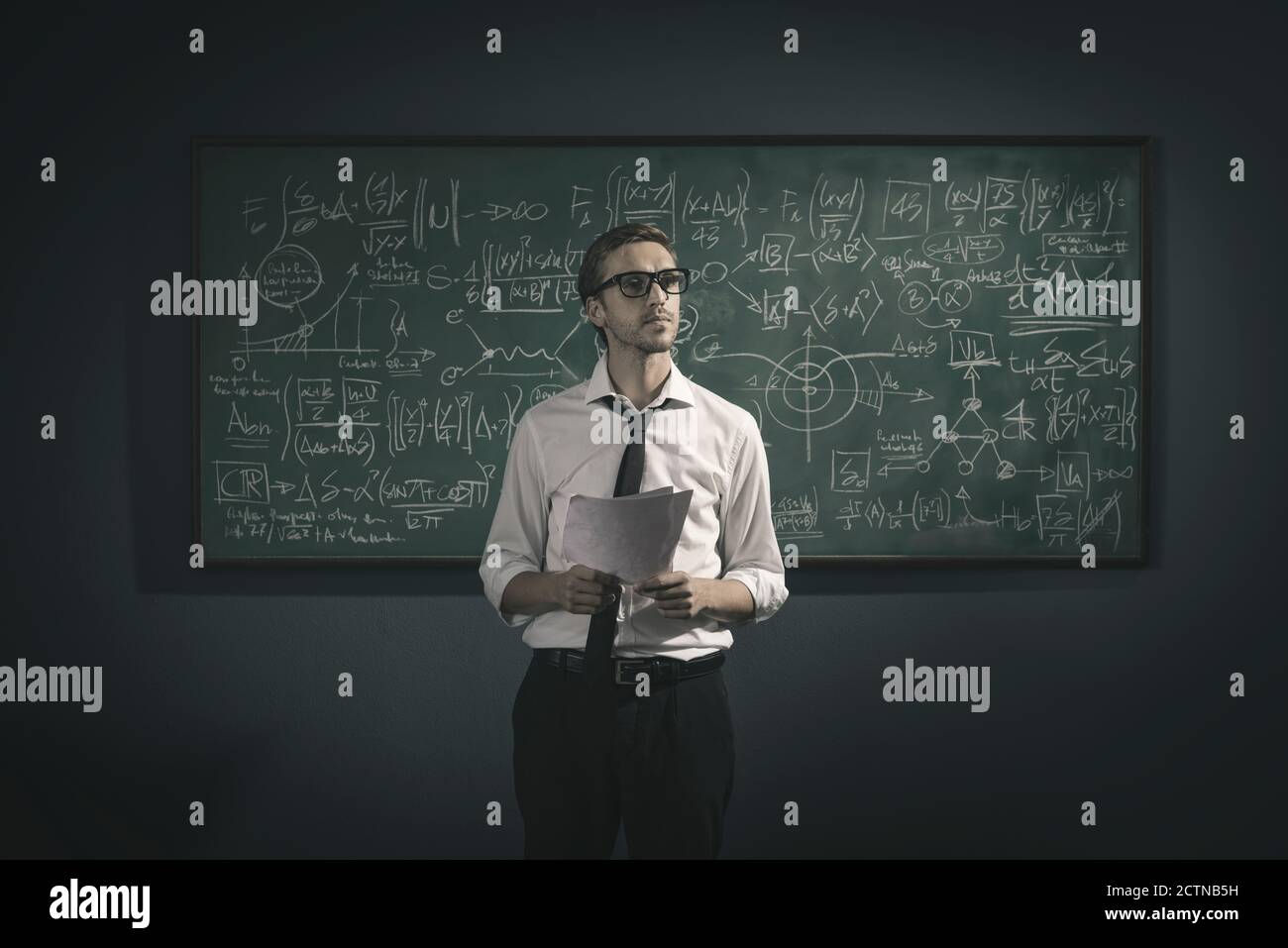 Confident young math professor standing in front of the chalkboard and ...