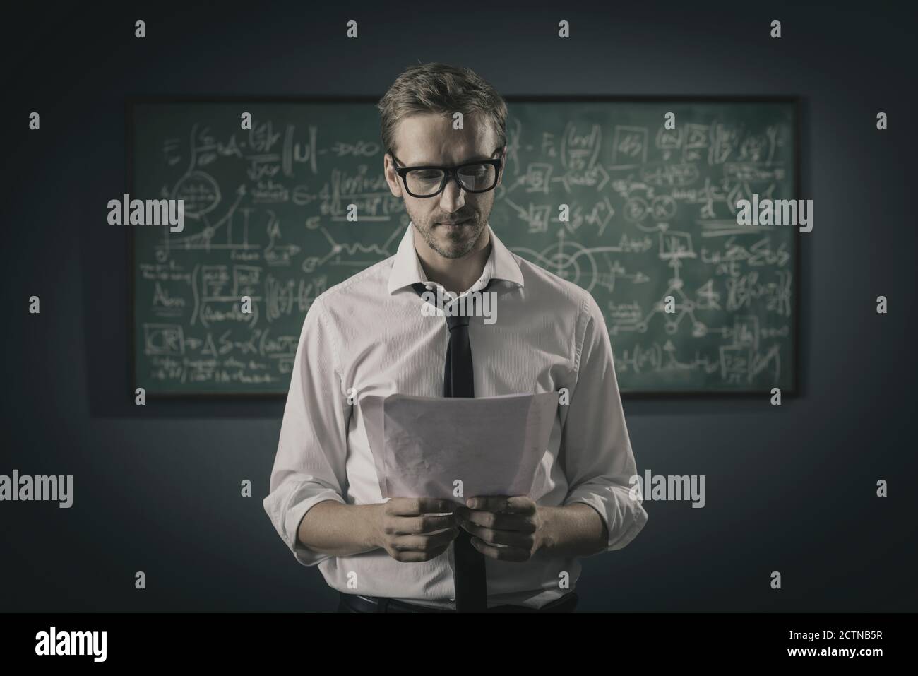 Confident young math professor standing in front of the chalkboard and ...