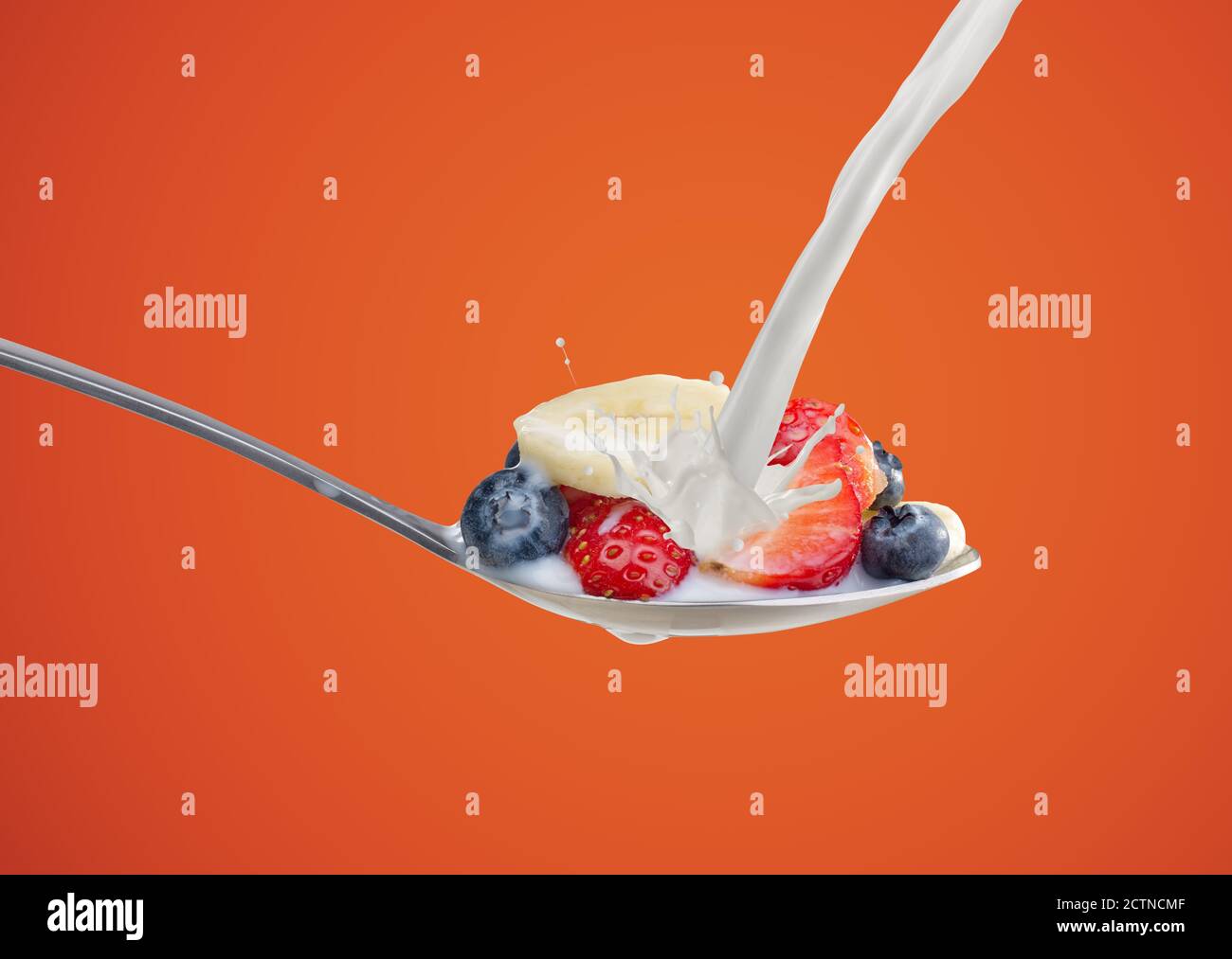 Fruits on a spoon with milk pouring Stock Photo - Alamy