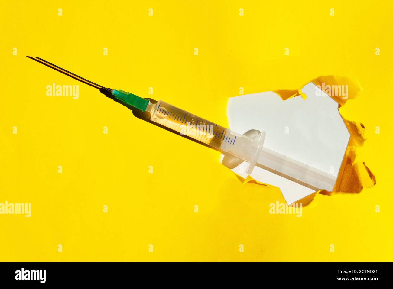 Top view of syringe with vaccine placed on torn yellow paper background ...