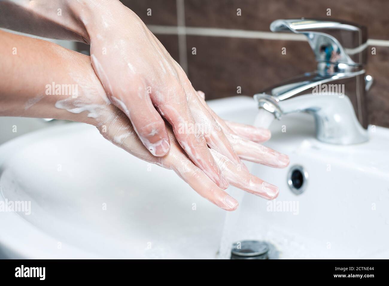 Hygiene concept. Washing hands with soap under the faucet with water ...