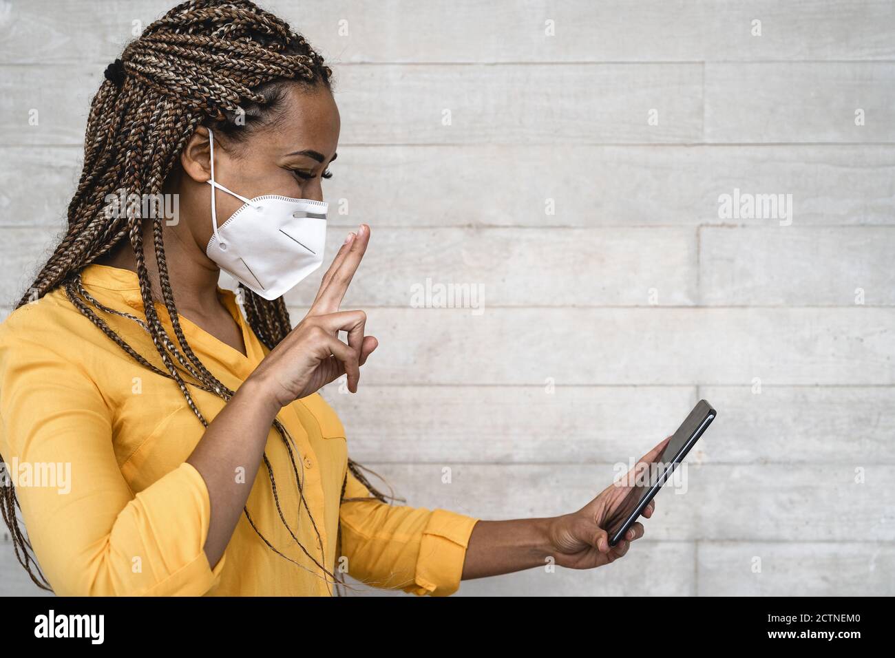 African woman wearing face medical mask using mobile smartphone - Young ...