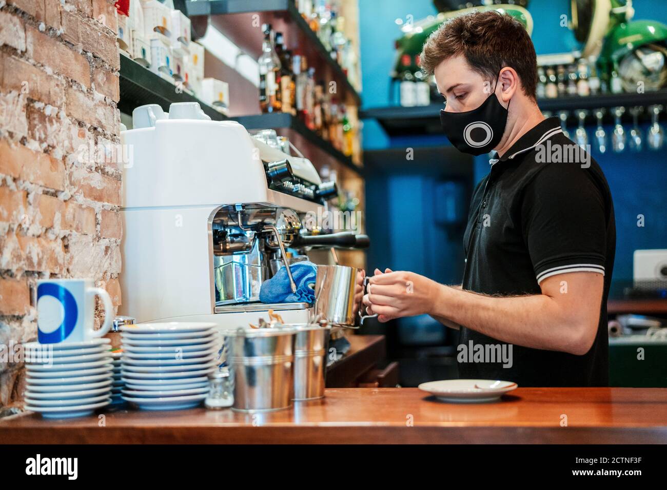 Side view of male barista preparing aromatic coffee in coffee maker ...
