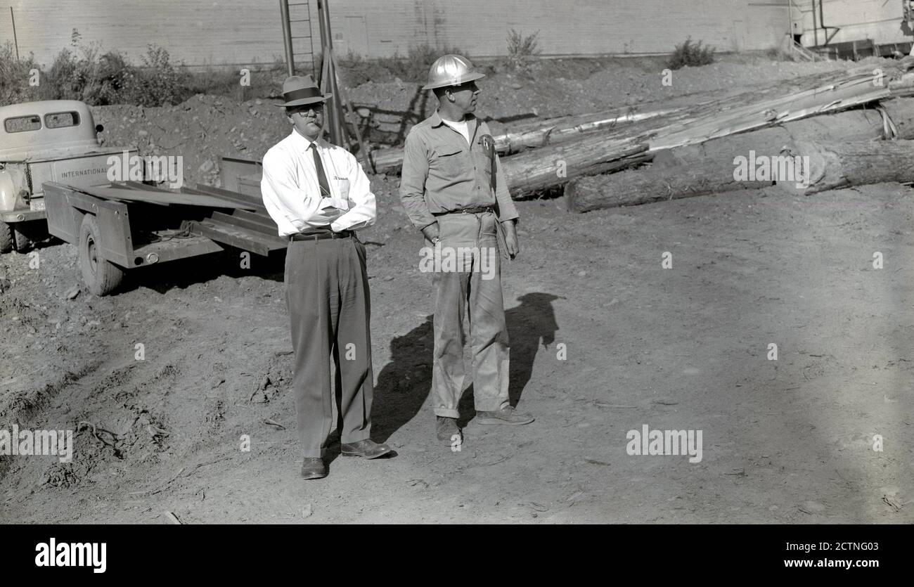 1950s, historical, construction manager and foreman standing outside at ...