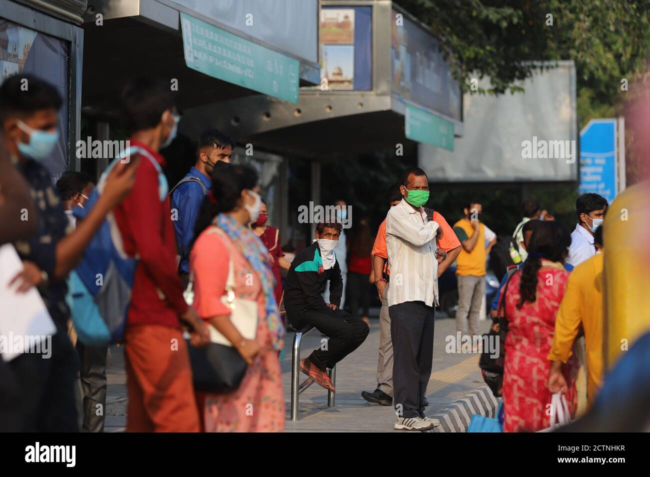 People stands at a bus stand as they are waiting for the public bus ...