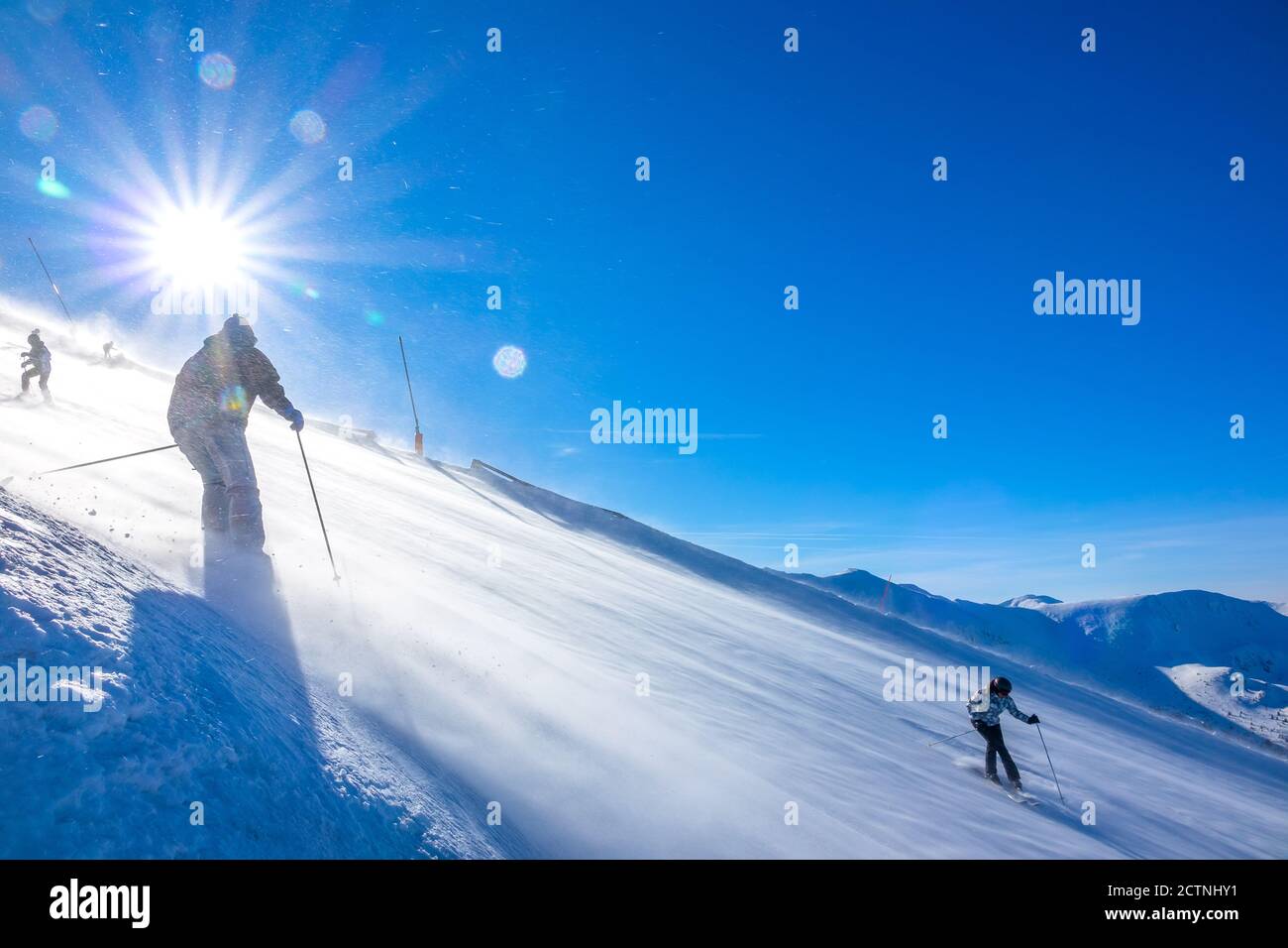 Sunny weather at the ski resort. A strong wind blows snow down a steep ...