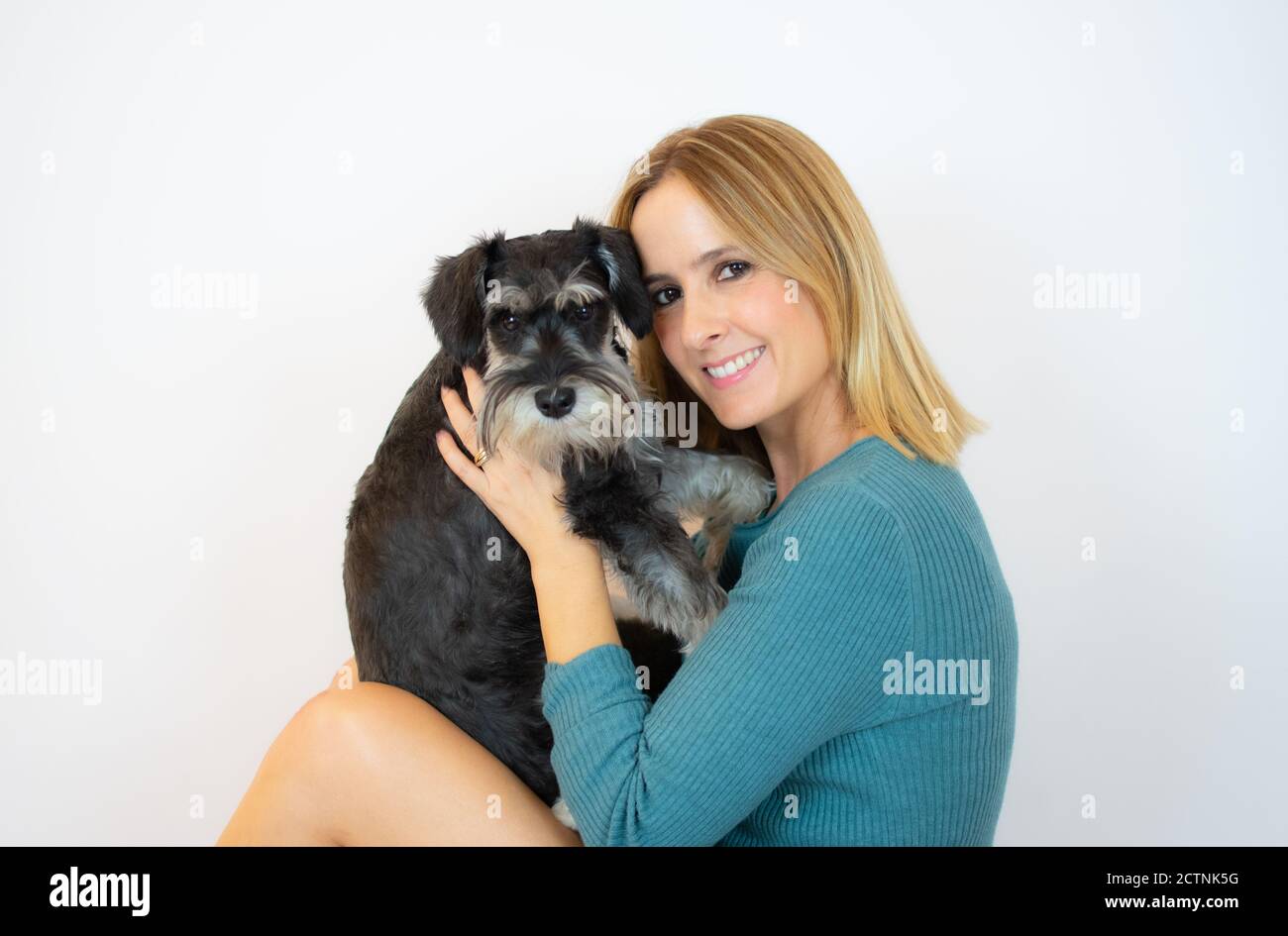 Cute young woman hugs her puppy schnauzer dog. Love between owner and ...