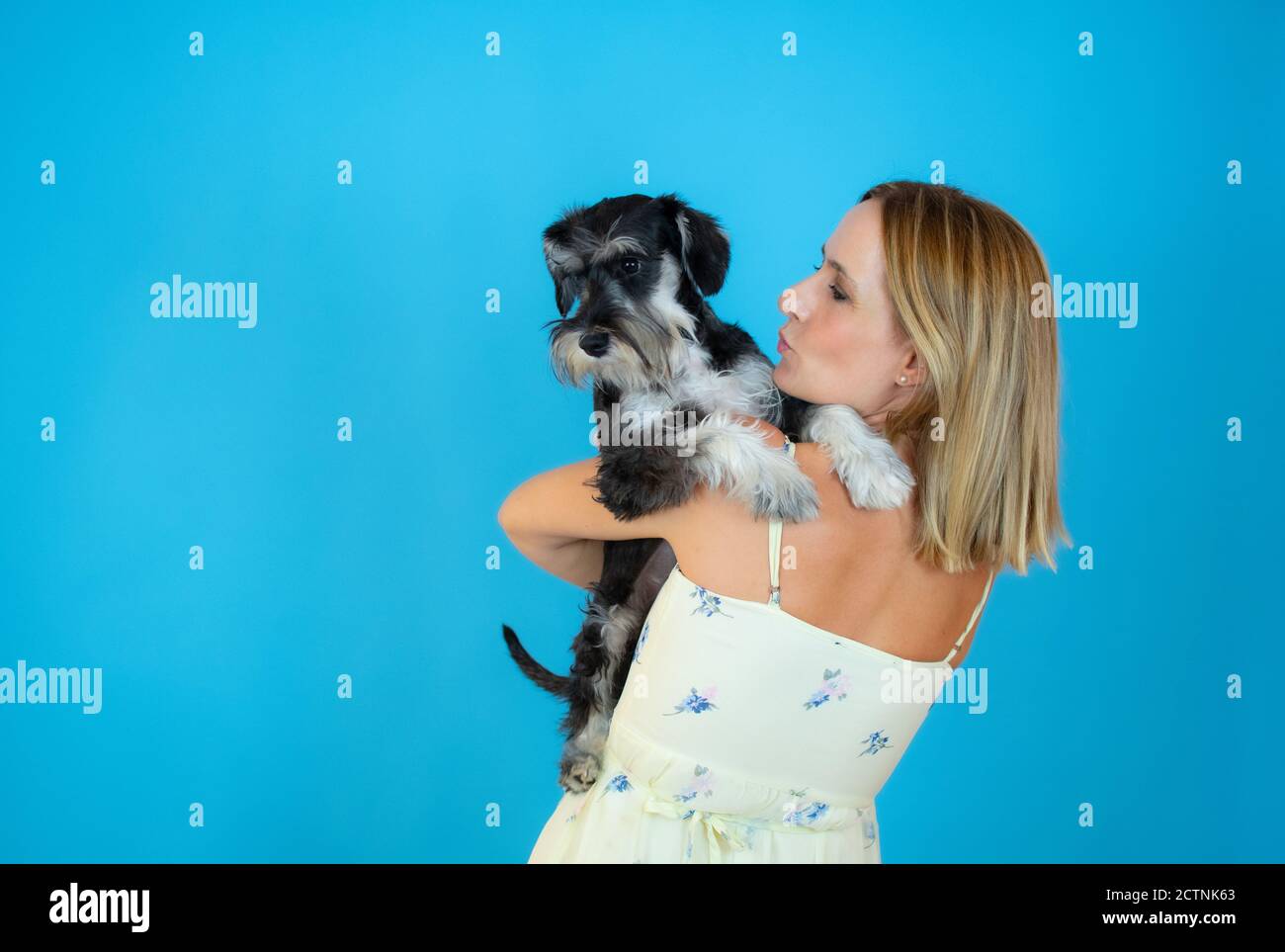 Cute young woman hugs her puppy schnauzer dog. Love between owner and ...