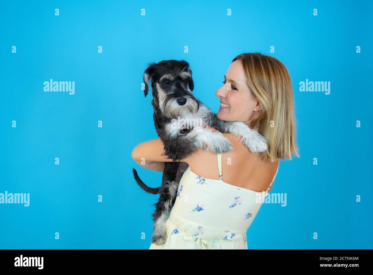 Cute young woman hugs her puppy schnauzer dog. Love between owner and ...