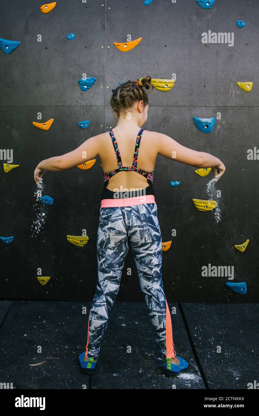 Back view of determined child in sportswear applying chalk on palms ...