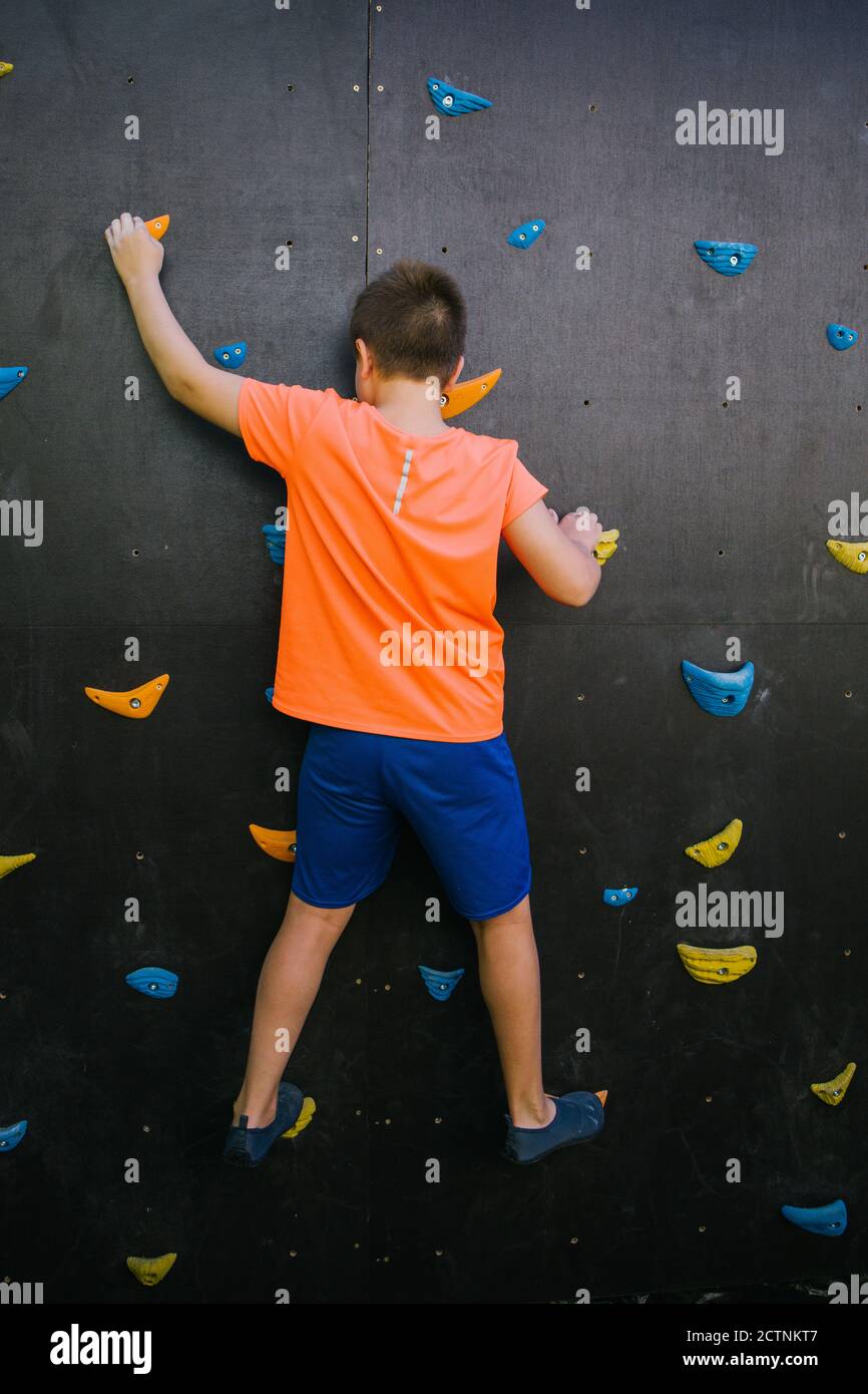 Back view of unrecognizable fearless child balancing on grips and ...