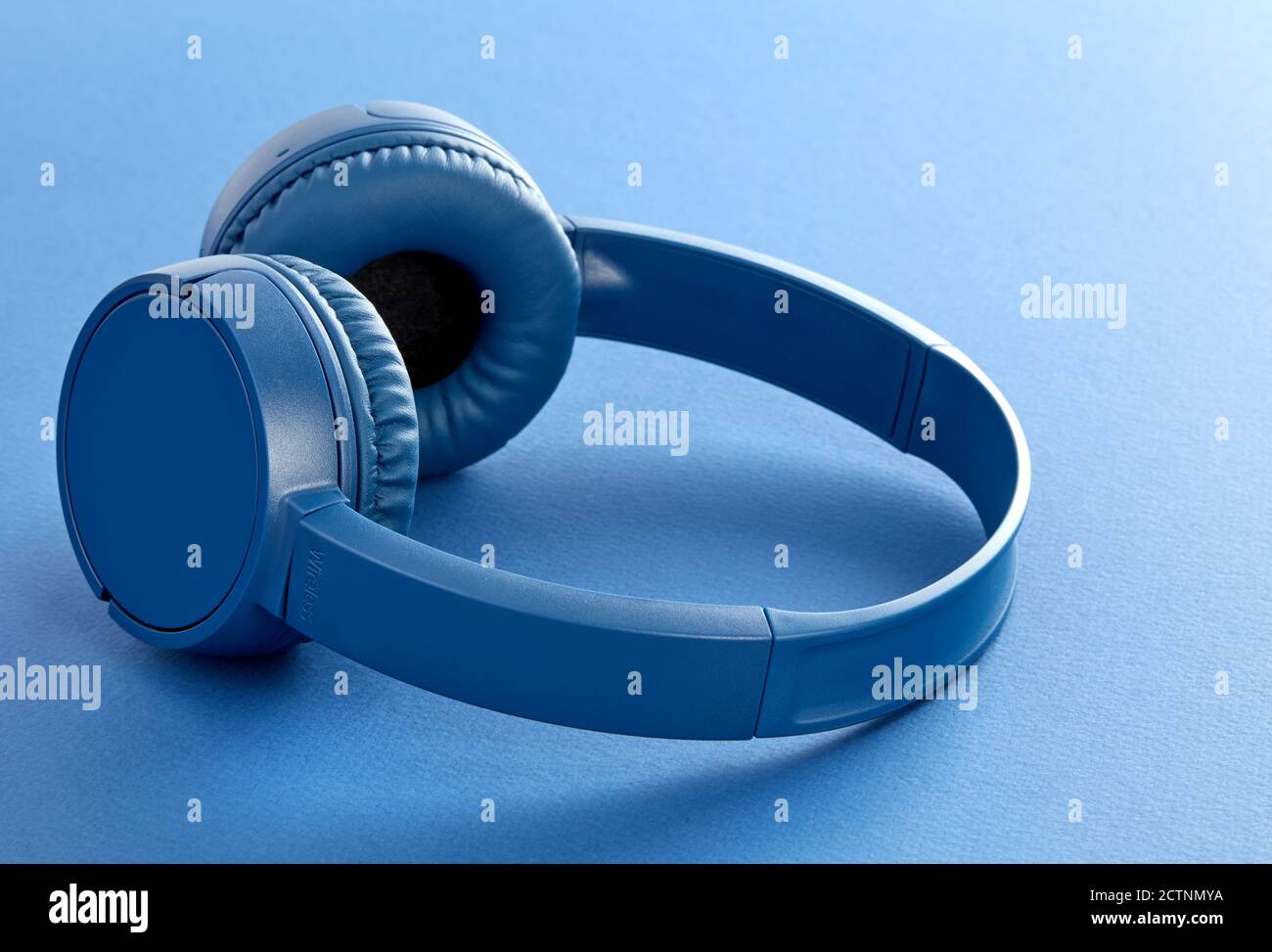 Blue wireless headphones on blue background Stock Photo - Alamy