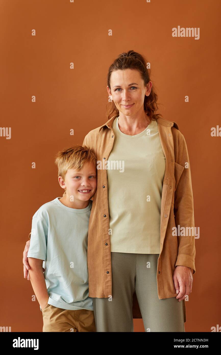 Vertical Portrait Of Happy Mature Mother Hugging Son While Standing