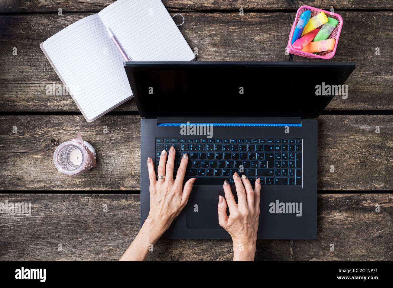 Top view of female hands typing on laptop computer with candle ...
